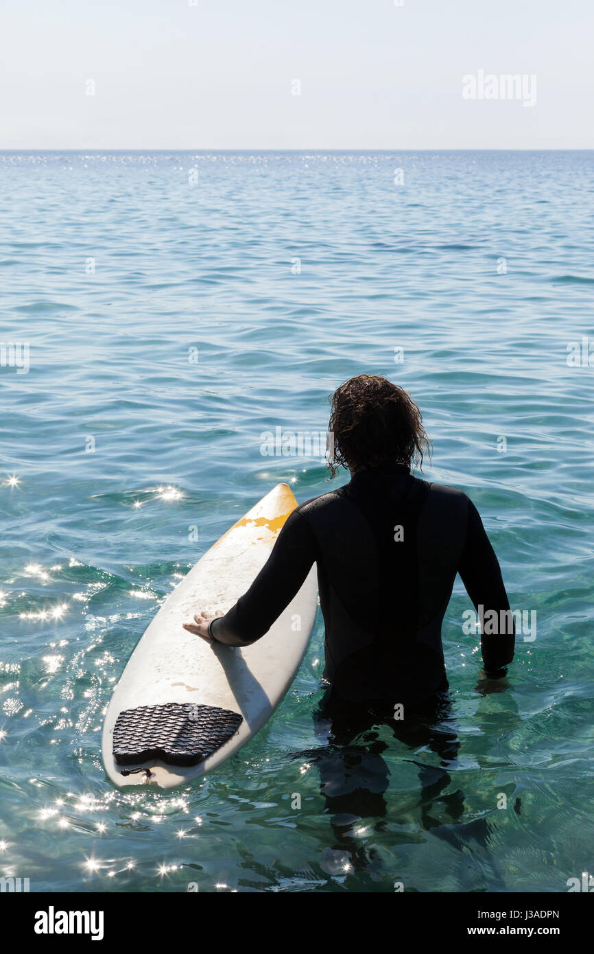 Rear view of surfer with surfboard standing in sea Stock Photo - Alamy