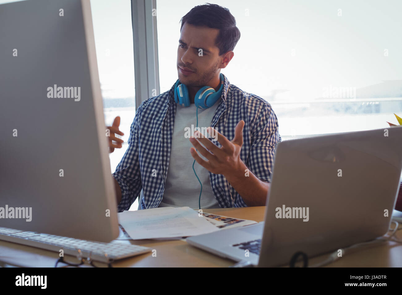 Confused graphic designer gesturing while sitting in office Stock Photo ...