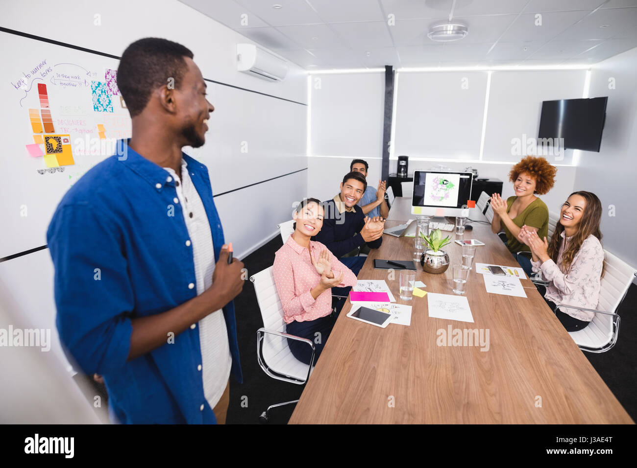 Colleagues clapping after presentation in confrence room at creative ...