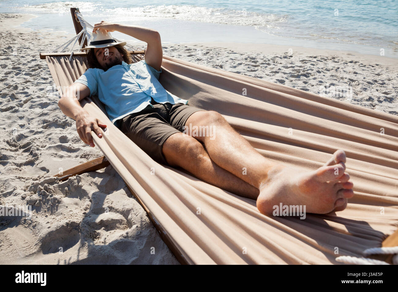 Man relaxing in hammock on beach Stock Photo - Alamy