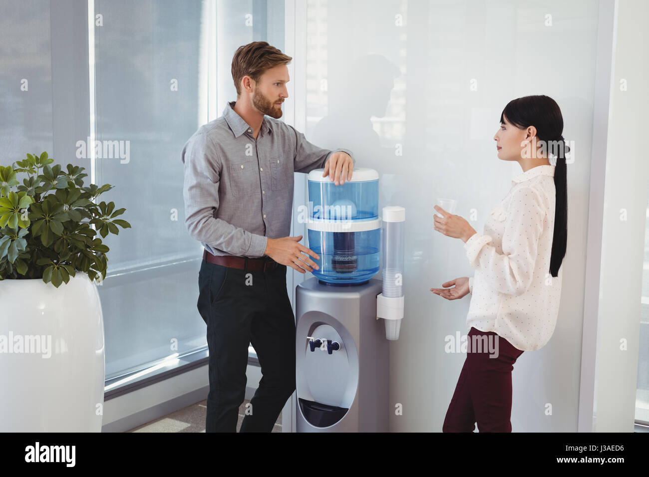 Colleagues interacting while drinking water in office Stock Photo - Alamy