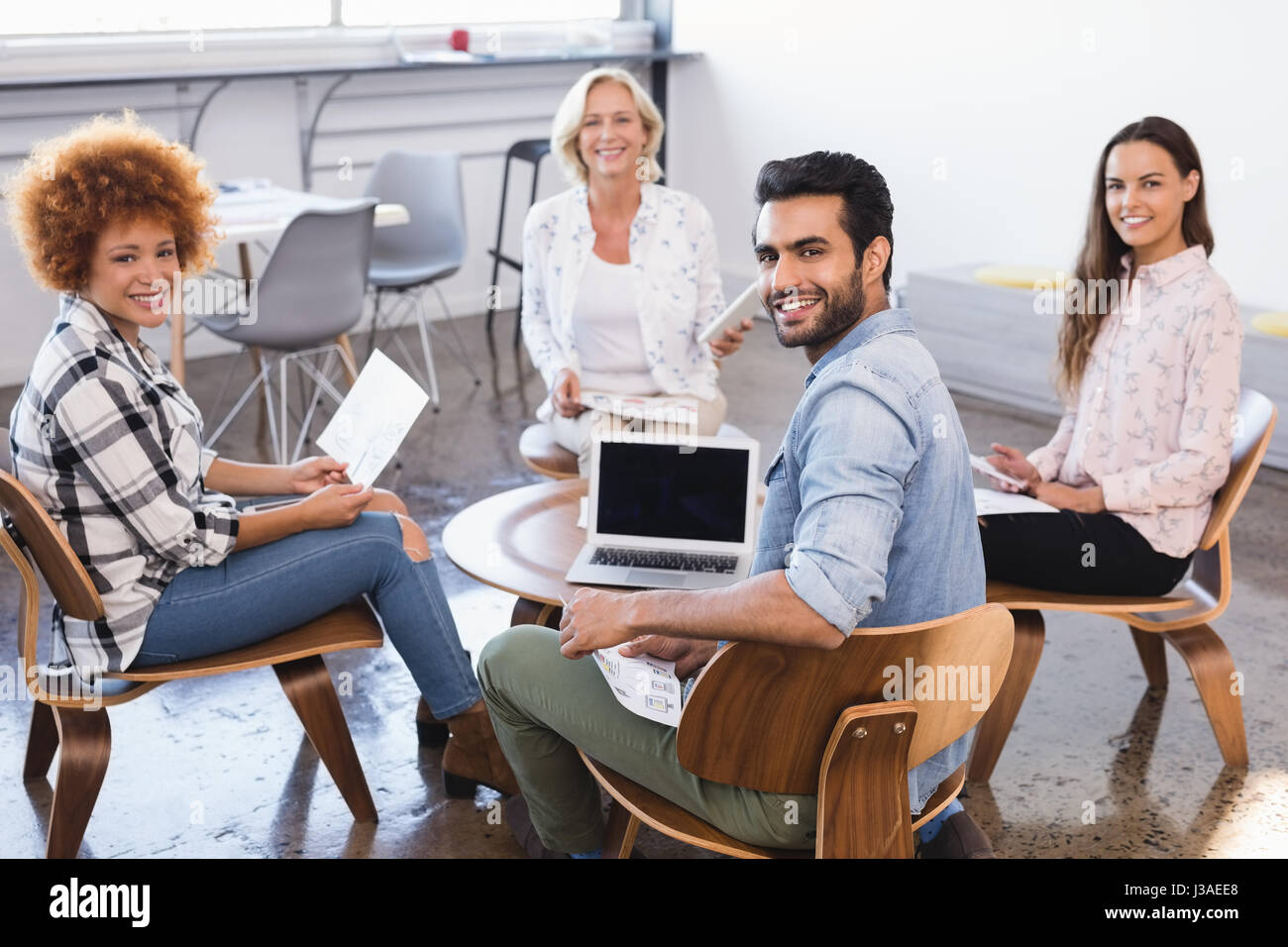 Portrait of smiling business team sitting around table while working ...