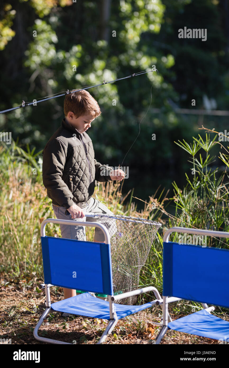 Little boy holding fishing net by chairs on sunny day Stock Photo - Alamy
