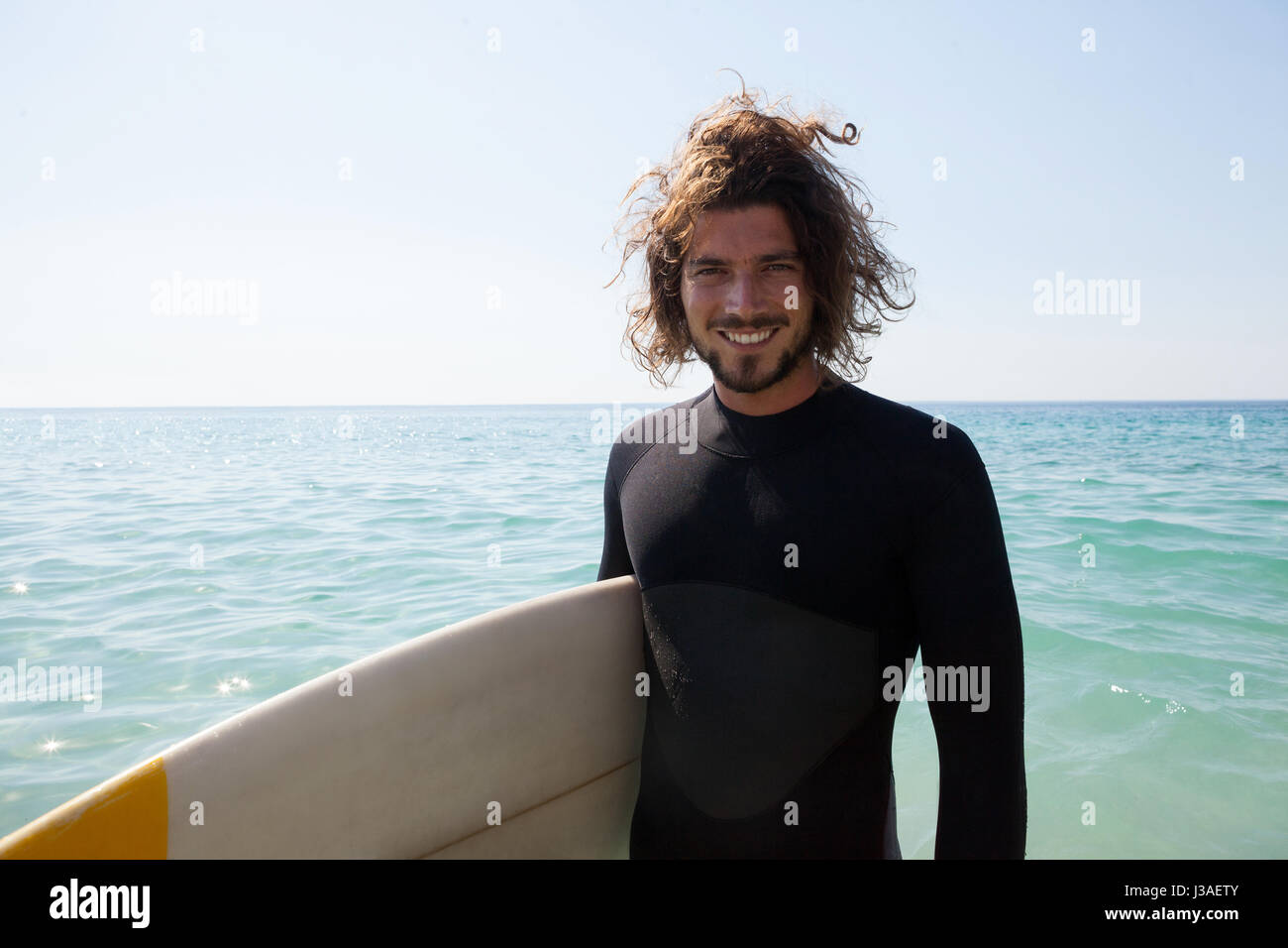 Portrait of smiling surfer with surfboard standing at beach coast Stock ...