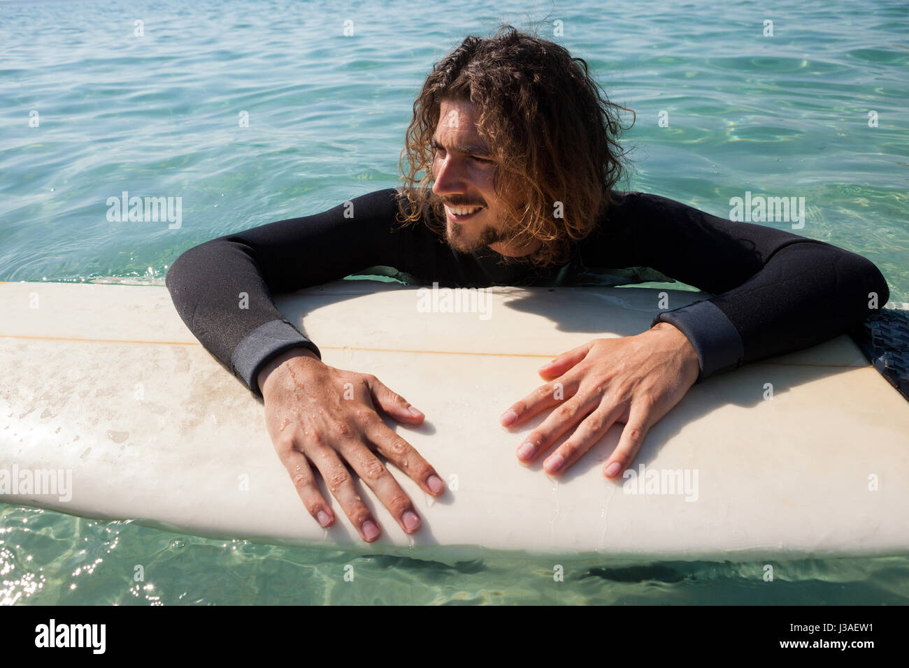 Smiling surfer leaning on surfboard in sea Stock Photo - Alamy