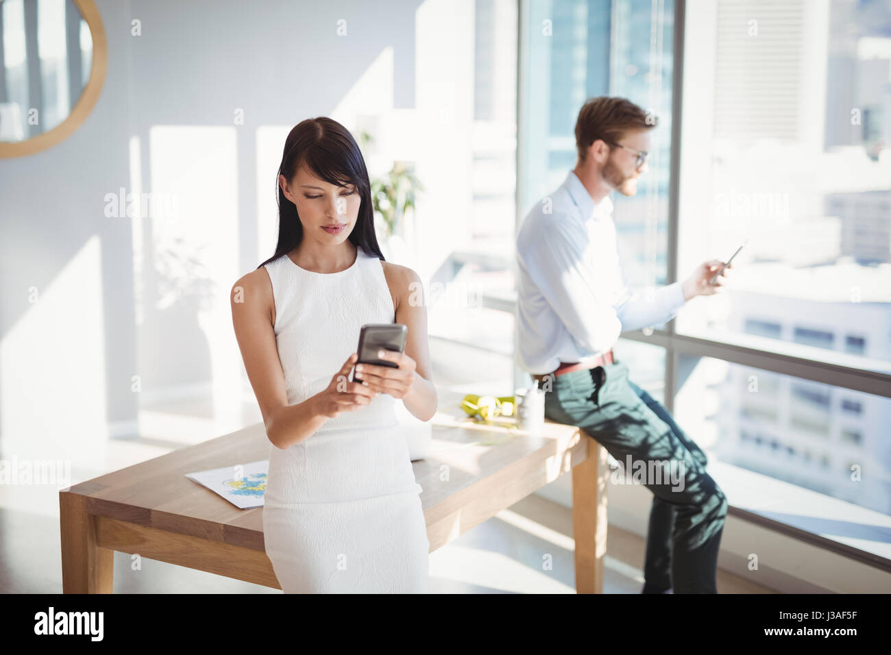 Attentive executives using mobile phone at desk in office Stock Photo ...