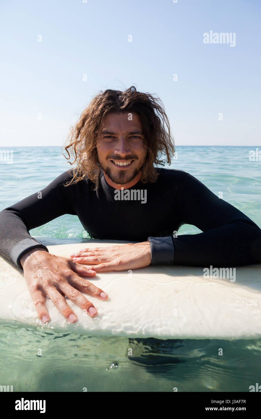 Portrait of smiling surfer leaning on surfboard in sea Stock Photo - Alamy
