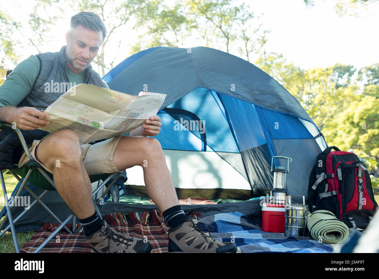 Man reading the map outside the tent at campsite Stock Photo - Alamy