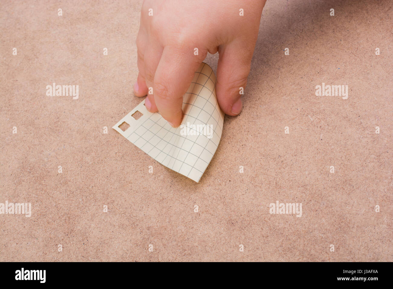 Hand holding a note paper on a brown background Stock Photo - Alamy