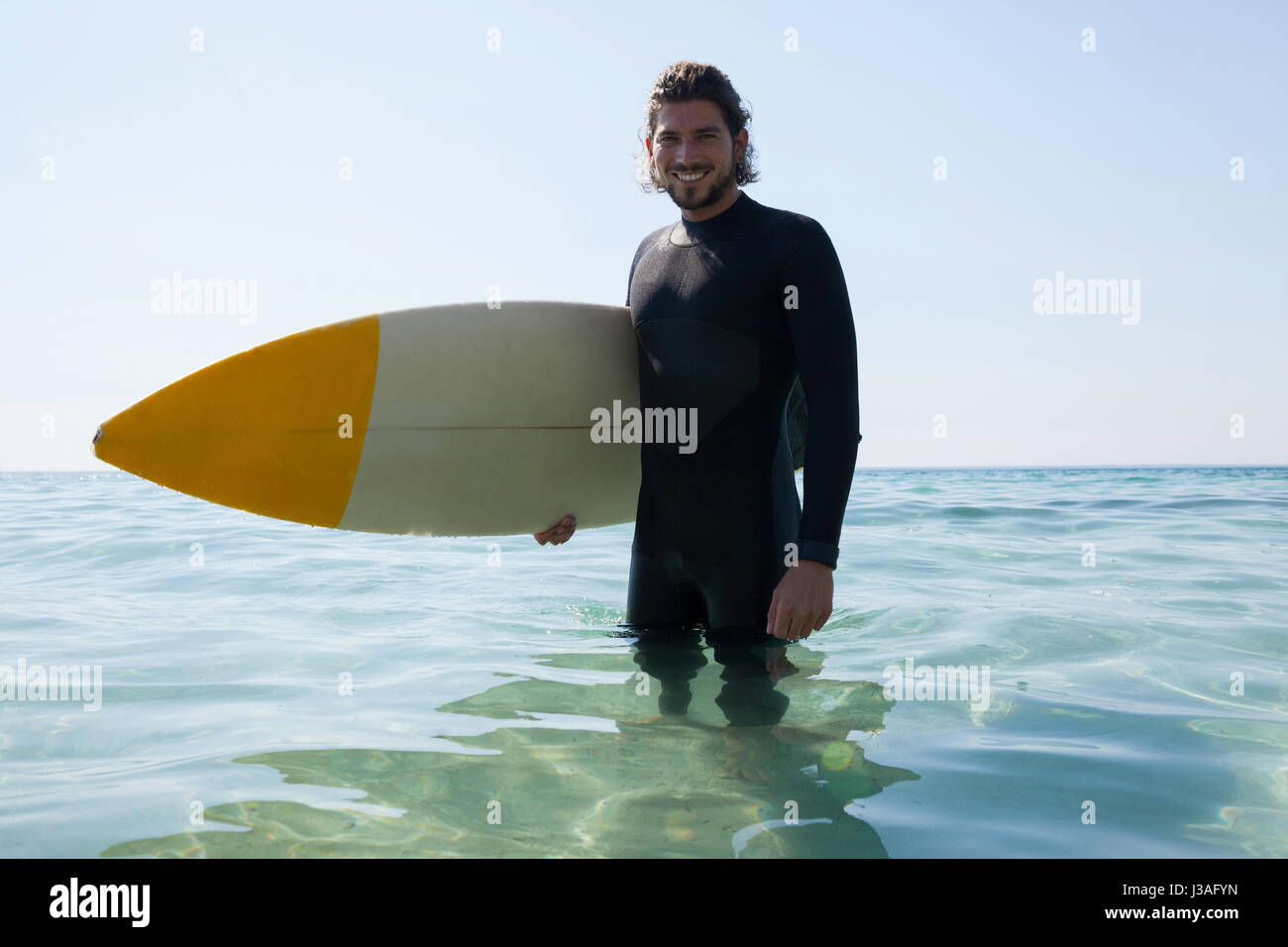 Portrait of smiling surfer with surfboard standing at beach coast Stock ...
