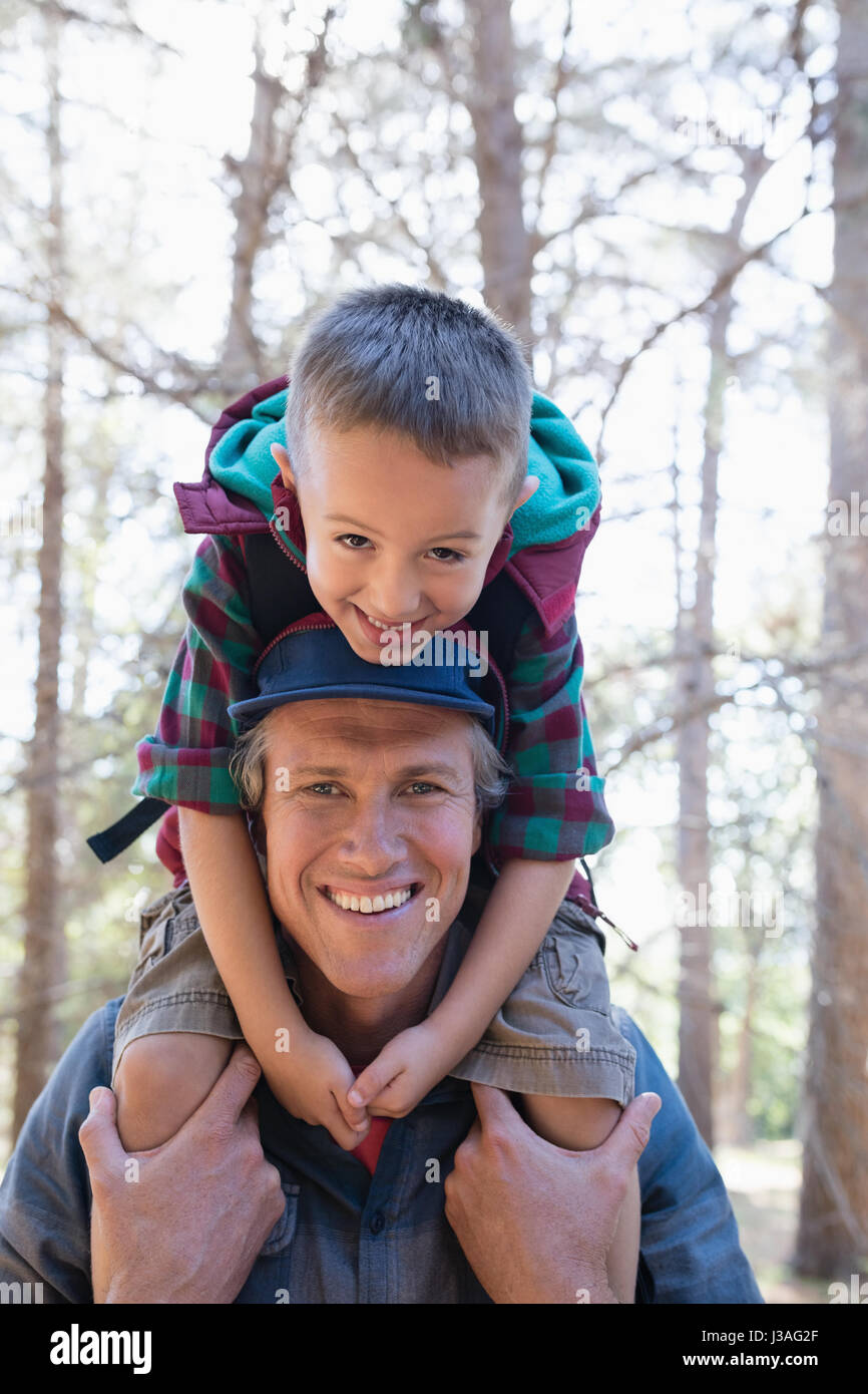 Happy boy sitting on shoulders of mature father in forest Stock Photo ...