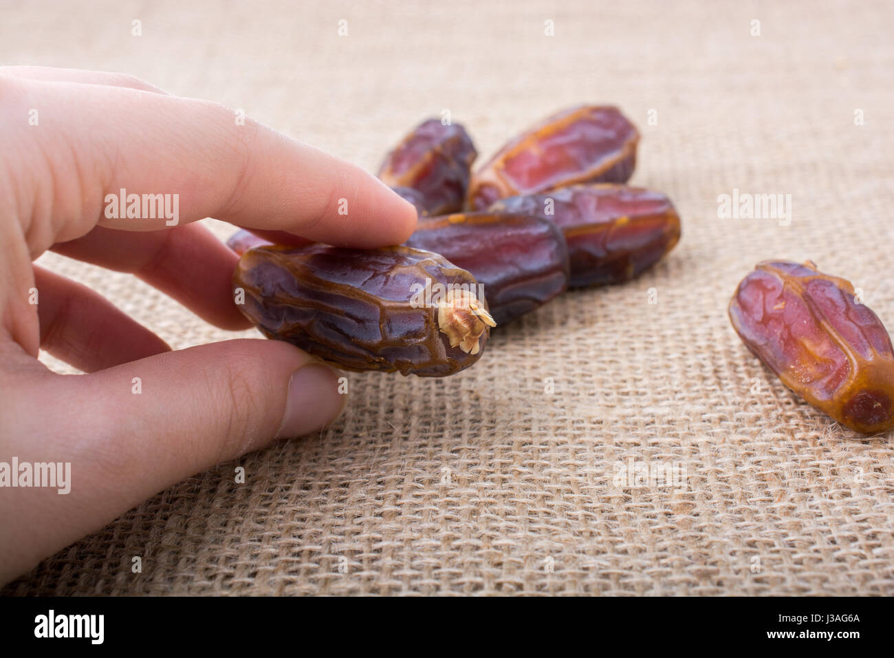 hand holding a date on a linen canvas background Stock Photo - Alamy