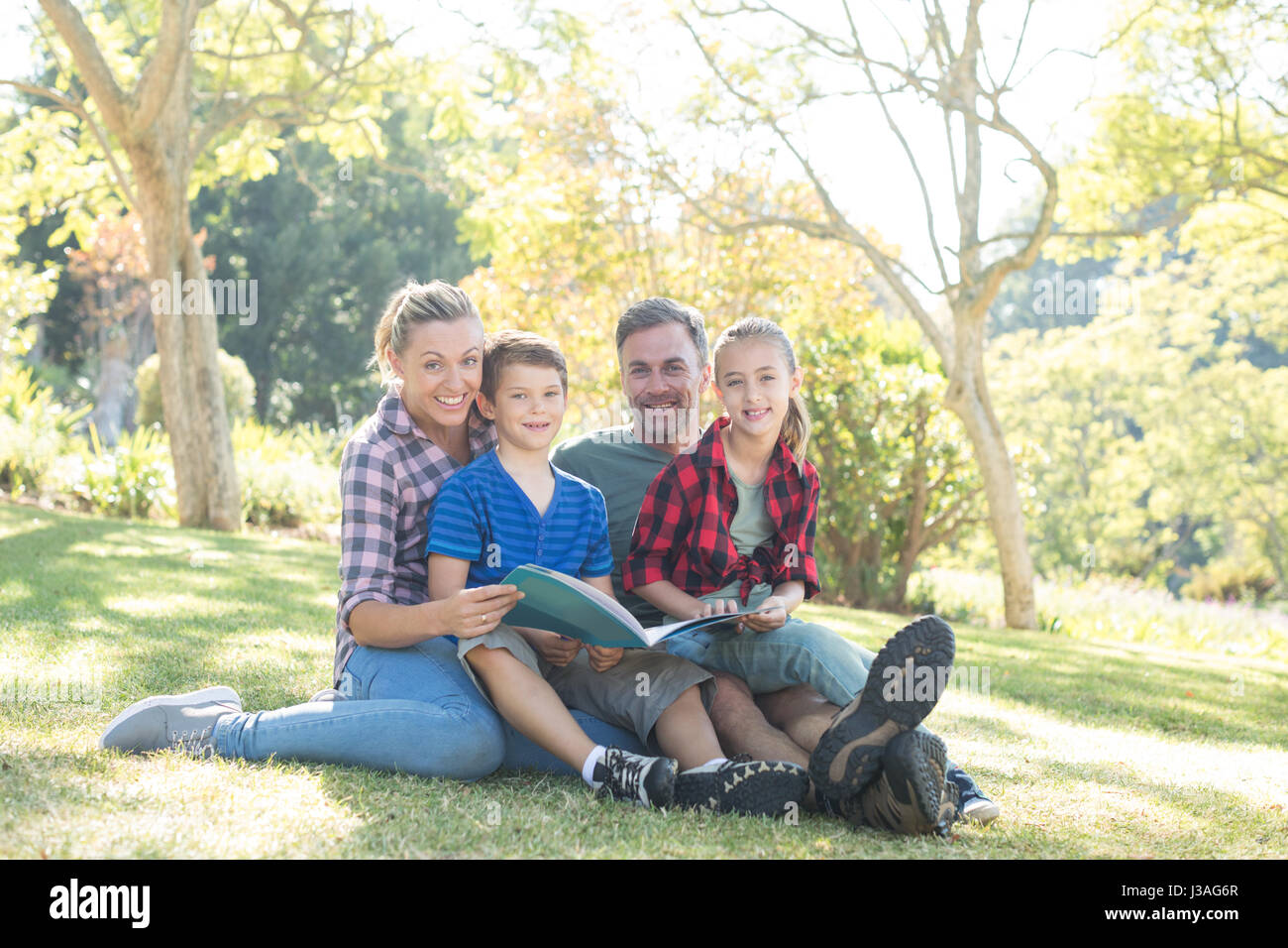 Happy family reading a book in the park on a sunny day Stock Photo - Alamy