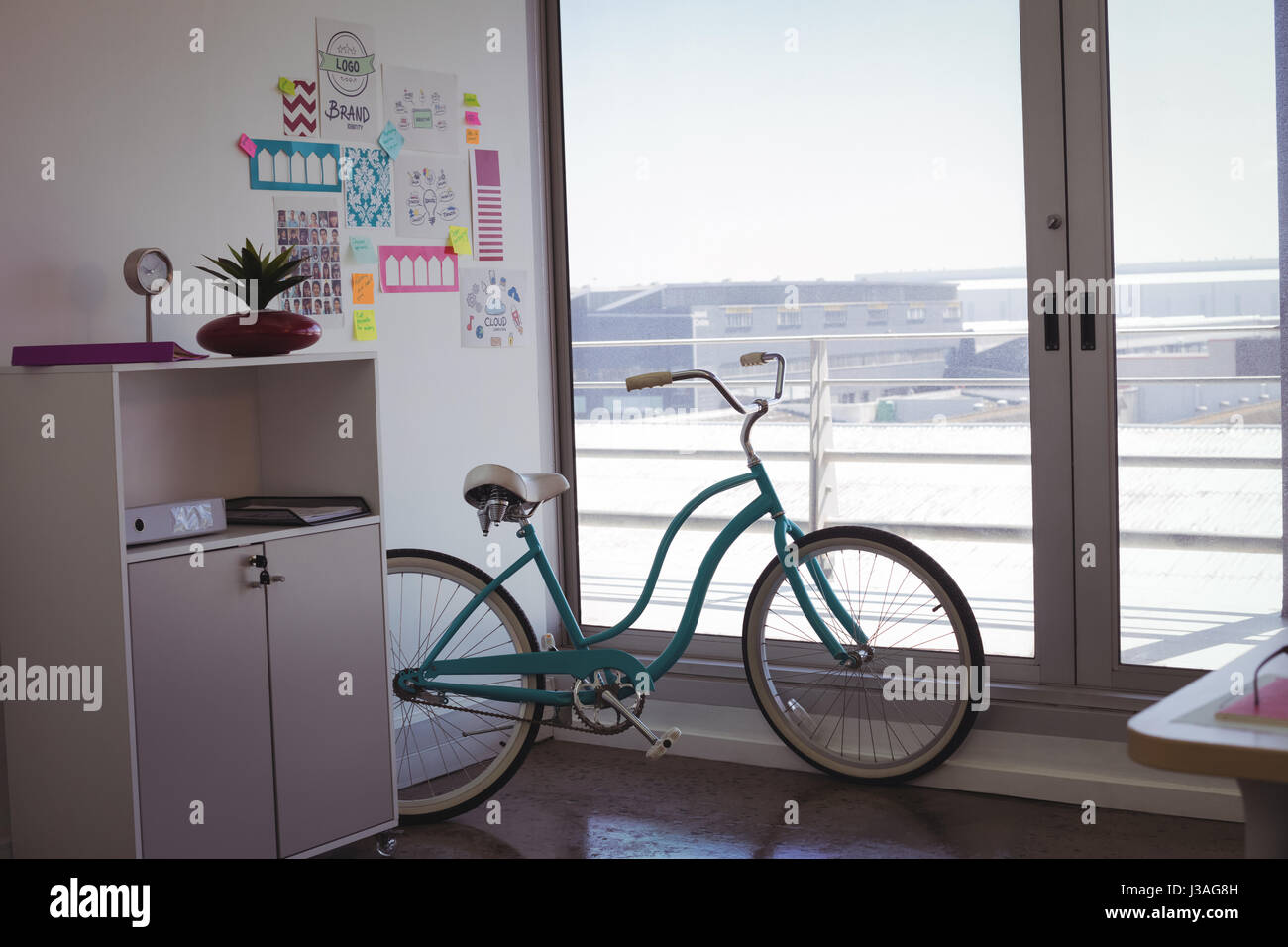 Bicycle by glass window in creative office Stock Photo - Alamy