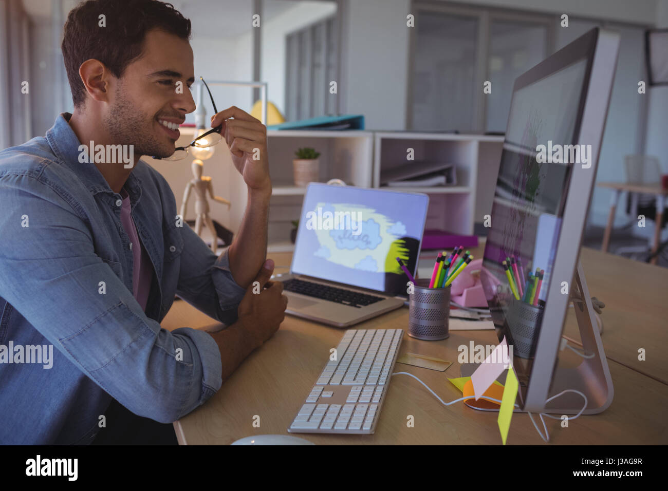 Smiling businessman looking at computer screen while working in ...