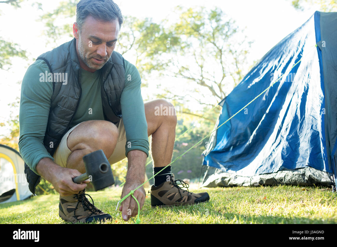 Man setting up the tent at campsite Stock Photo - Alamy
