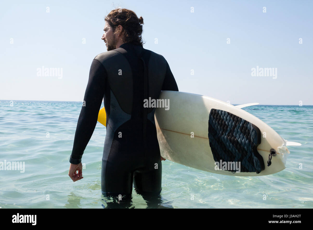 Rear view of surfer with surfboard looking at sea from the beach Stock ...