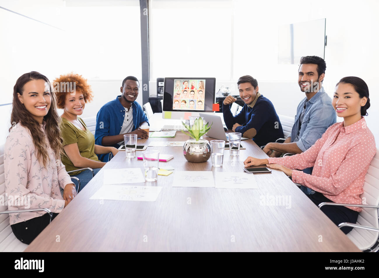 Portrait of business people sitting at desk during meeting in office ...