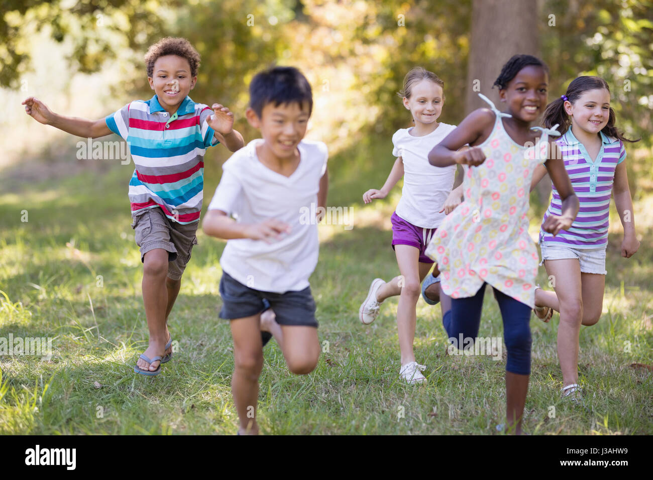 Happy friends running on grassy field at campsite Stock Photo - Alamy