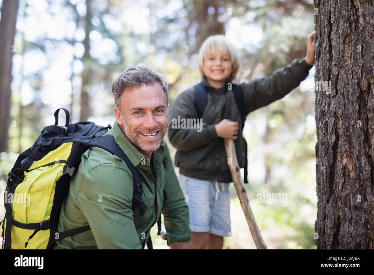 Portrait of smiling father and son carrying backpacks while hiking in ...