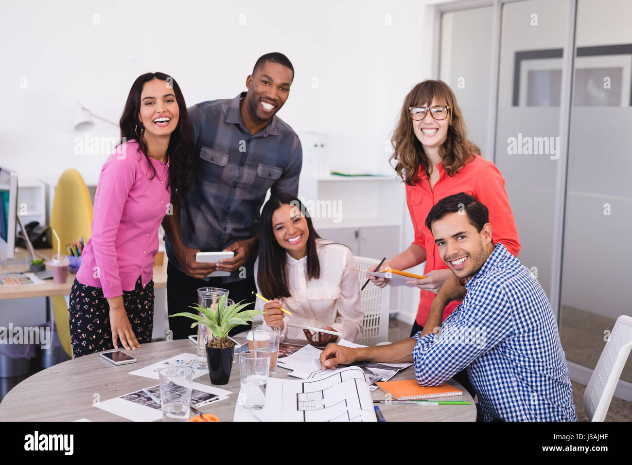 Smiling business people at desk against wall in office Stock Photo - Alamy