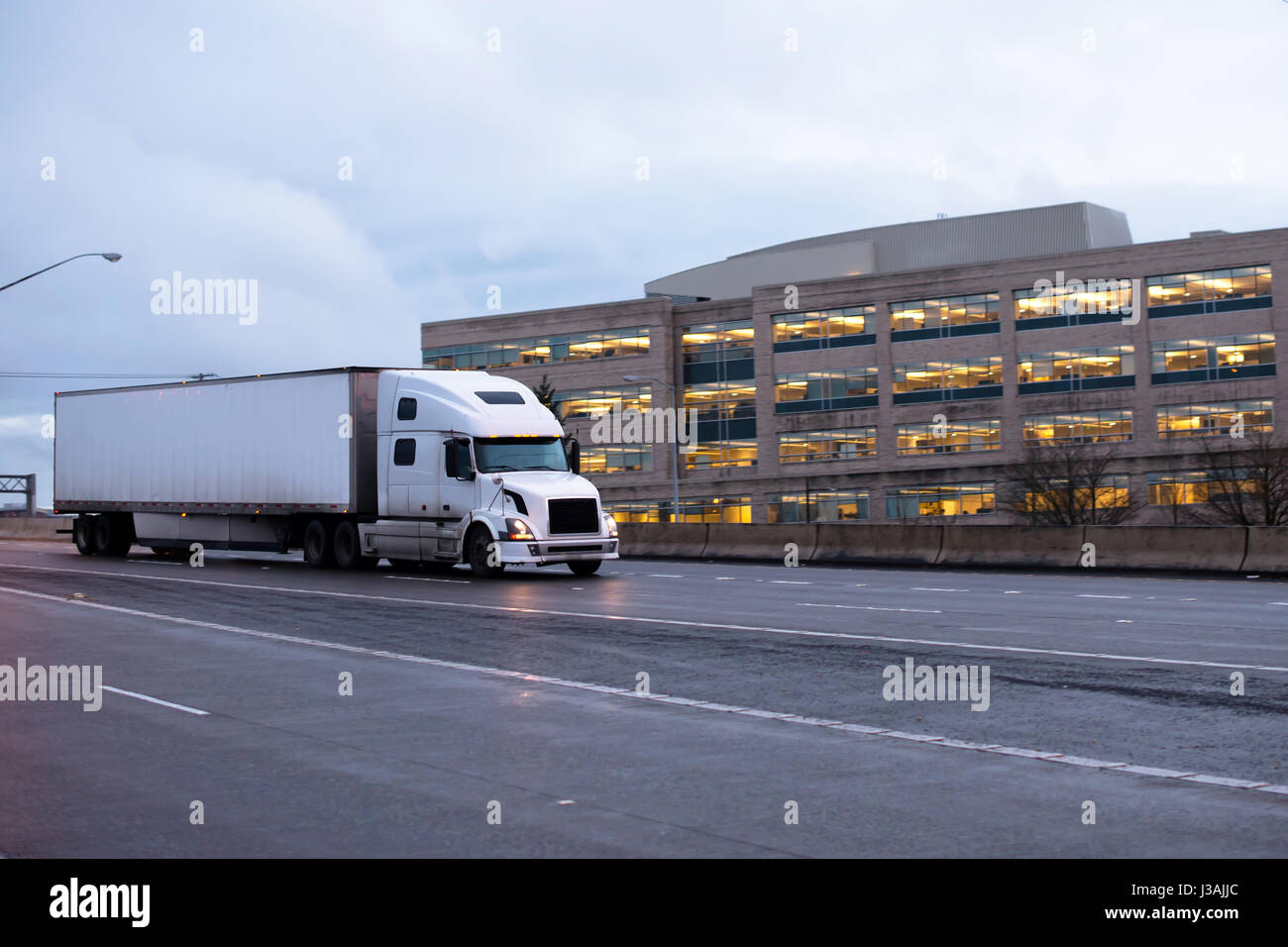 White modern semi truck with a dry van trailer moving on evening ...
