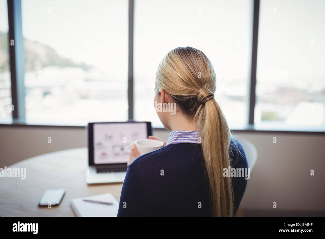Rear view of executive having coffee in office Stock Photo - Alamy