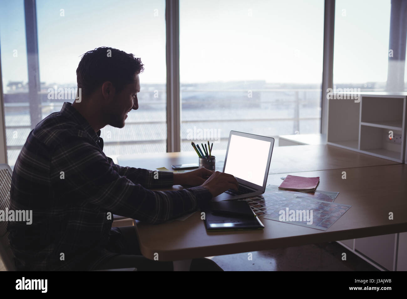 Side view of young businessman using laptop on desk in office Stock ...