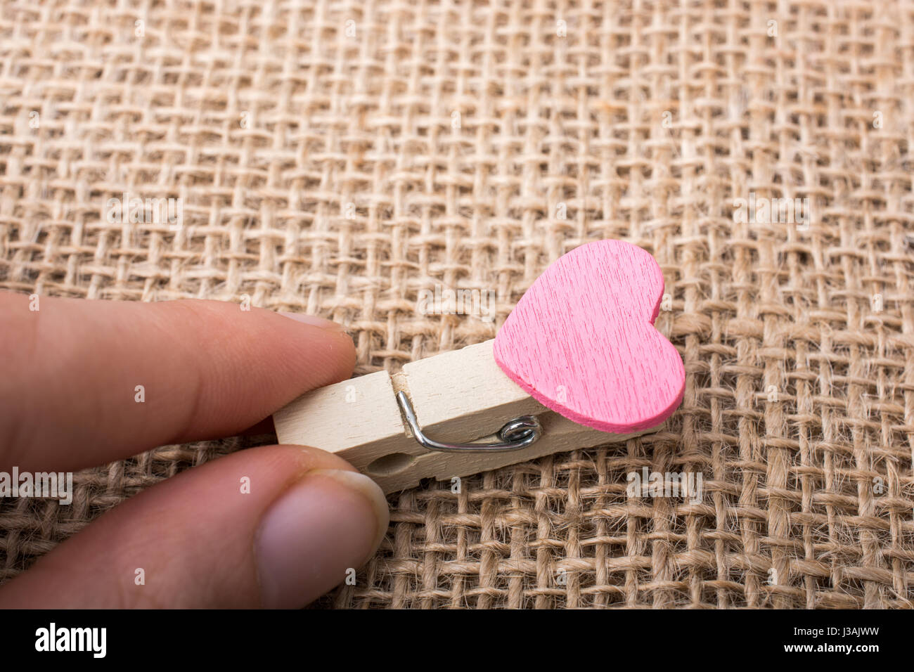 Colorful heart attached to a clothespin in hand Stock Photo - Alamy