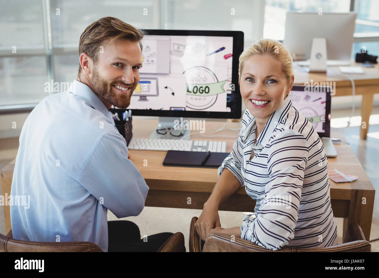 Portrait of executives sitting at desk in office Stock Photo - Alamy