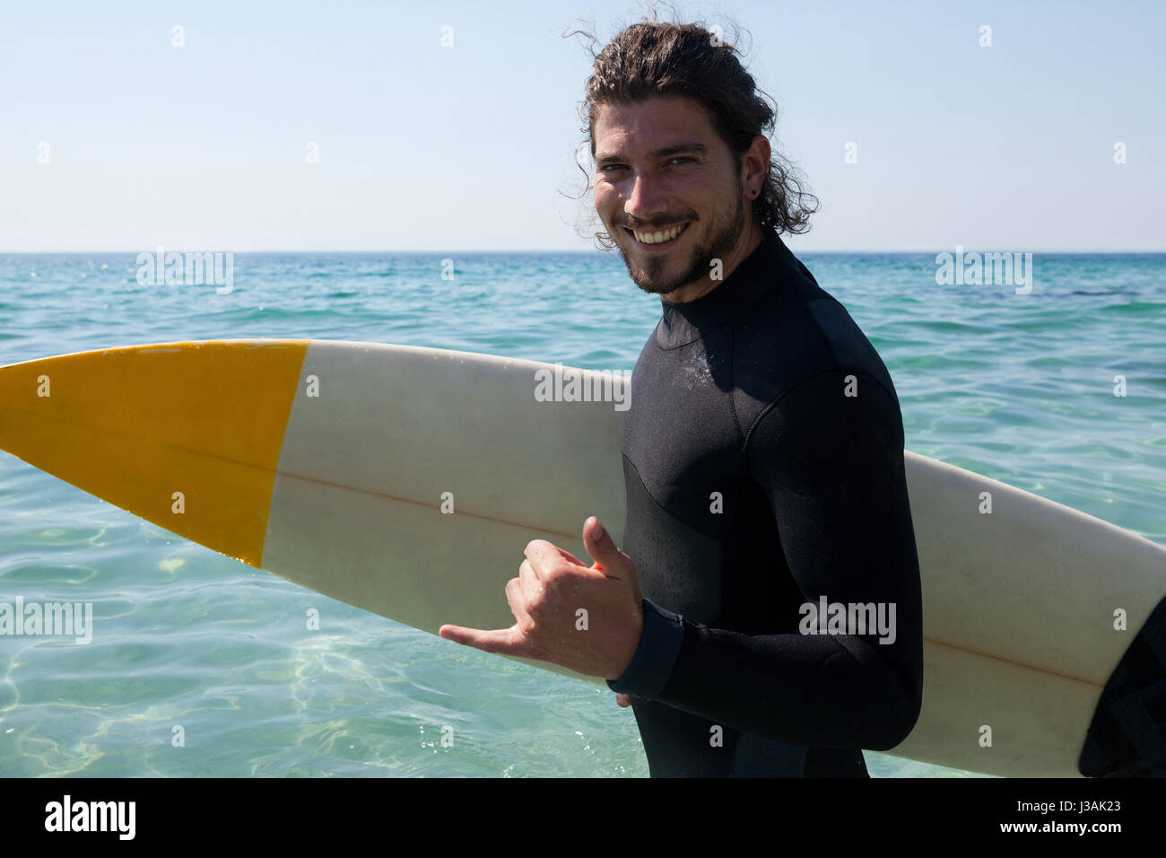 Portrait of smiling surfer with surfboard standing at beach coast Stock ...