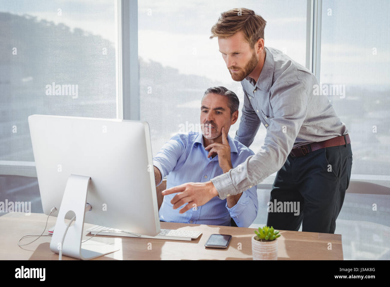 Executives discussing over personal computer at desk in office Stock ...