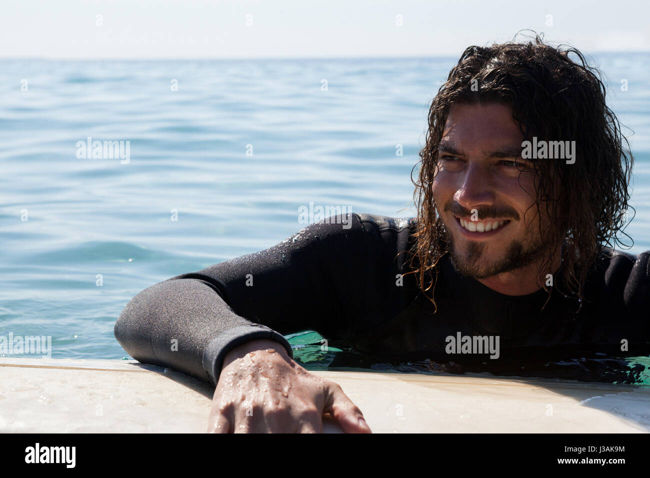 Smiling surfer leaning on surfboard in sea Stock Photo - Alamy
