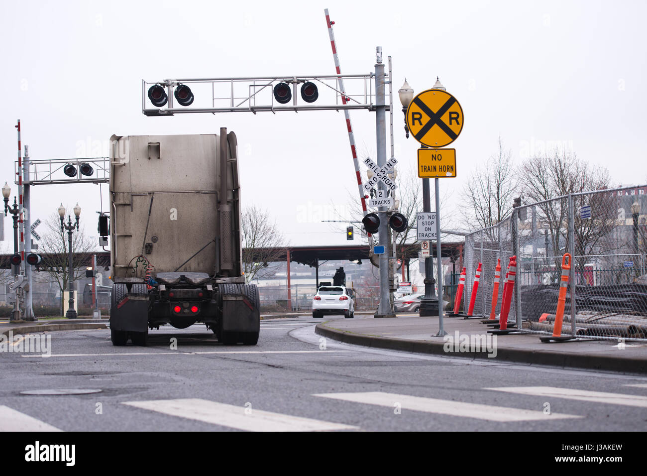 A dirty semi truck tractor without a trailer crosses an open railroad ...
