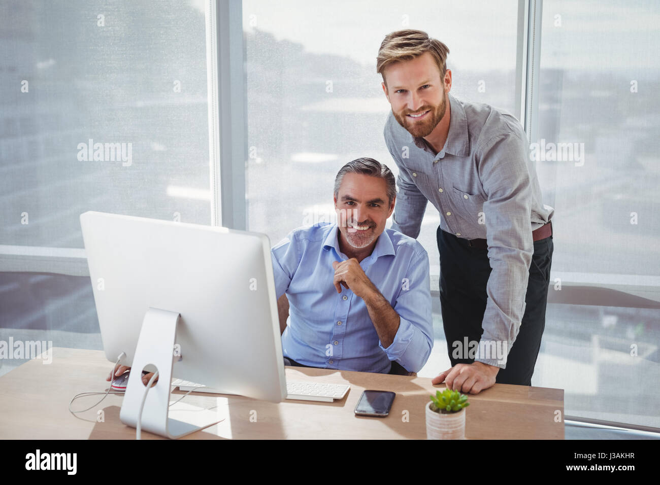 Portrait of smiling executives at desk in office Stock Photo - Alamy
