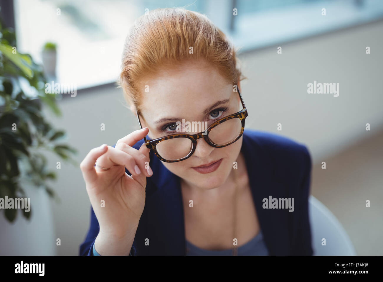 Portrait of executive holding spectacles in office Stock Photo - Alamy