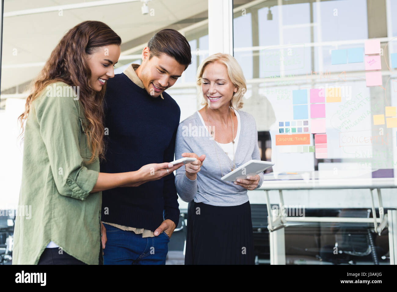 Business people discussing over tablet pc while standing against glass ...