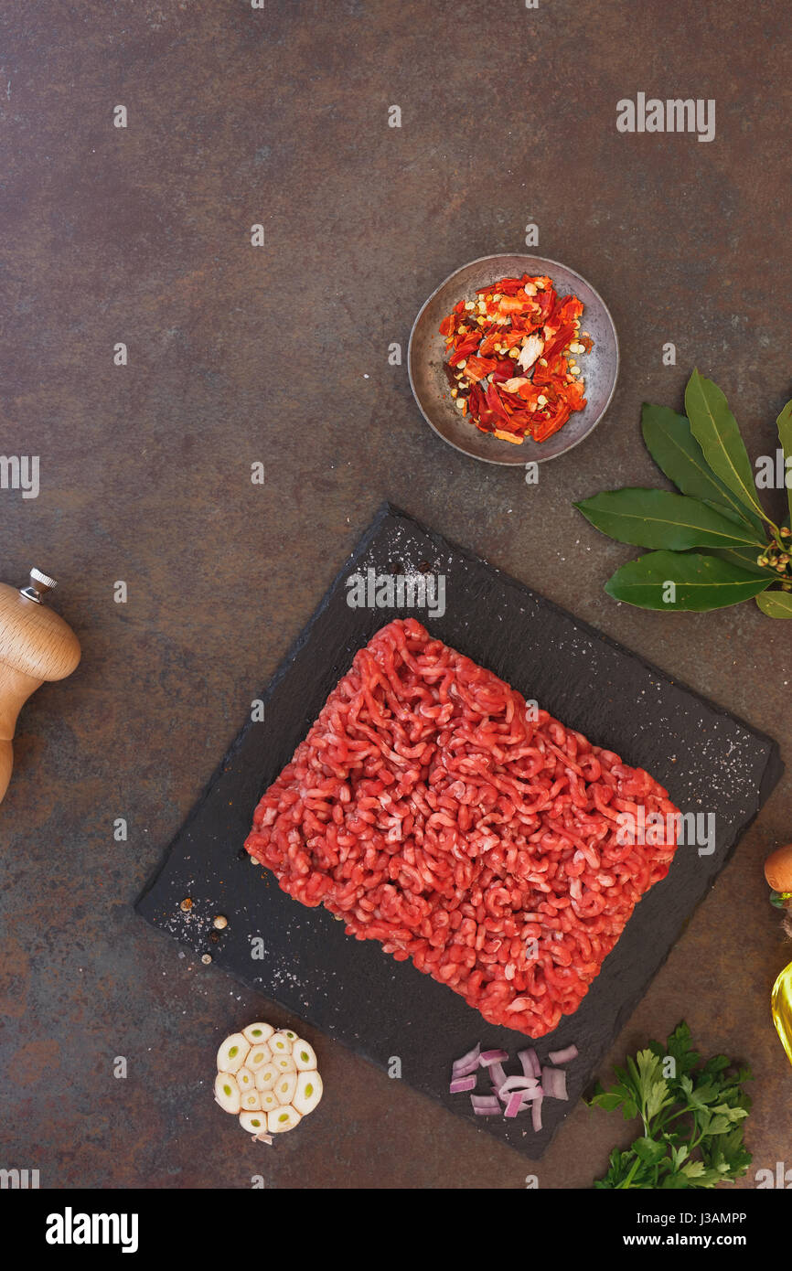 Fresh ground beef and seasonings on rustic textured background Top view ...