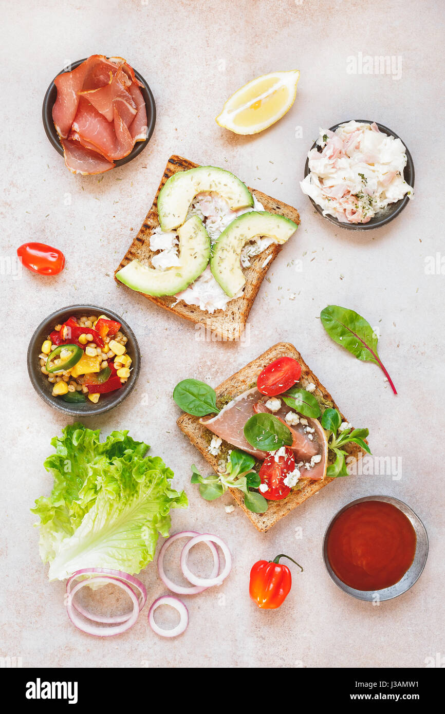Open wholemeal sandwiches and various ingredients on rustic surface ...