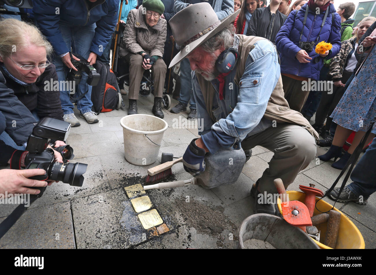 Artist Gunter Demnig cleans three so-called Stolpersteine - cobblestone ...