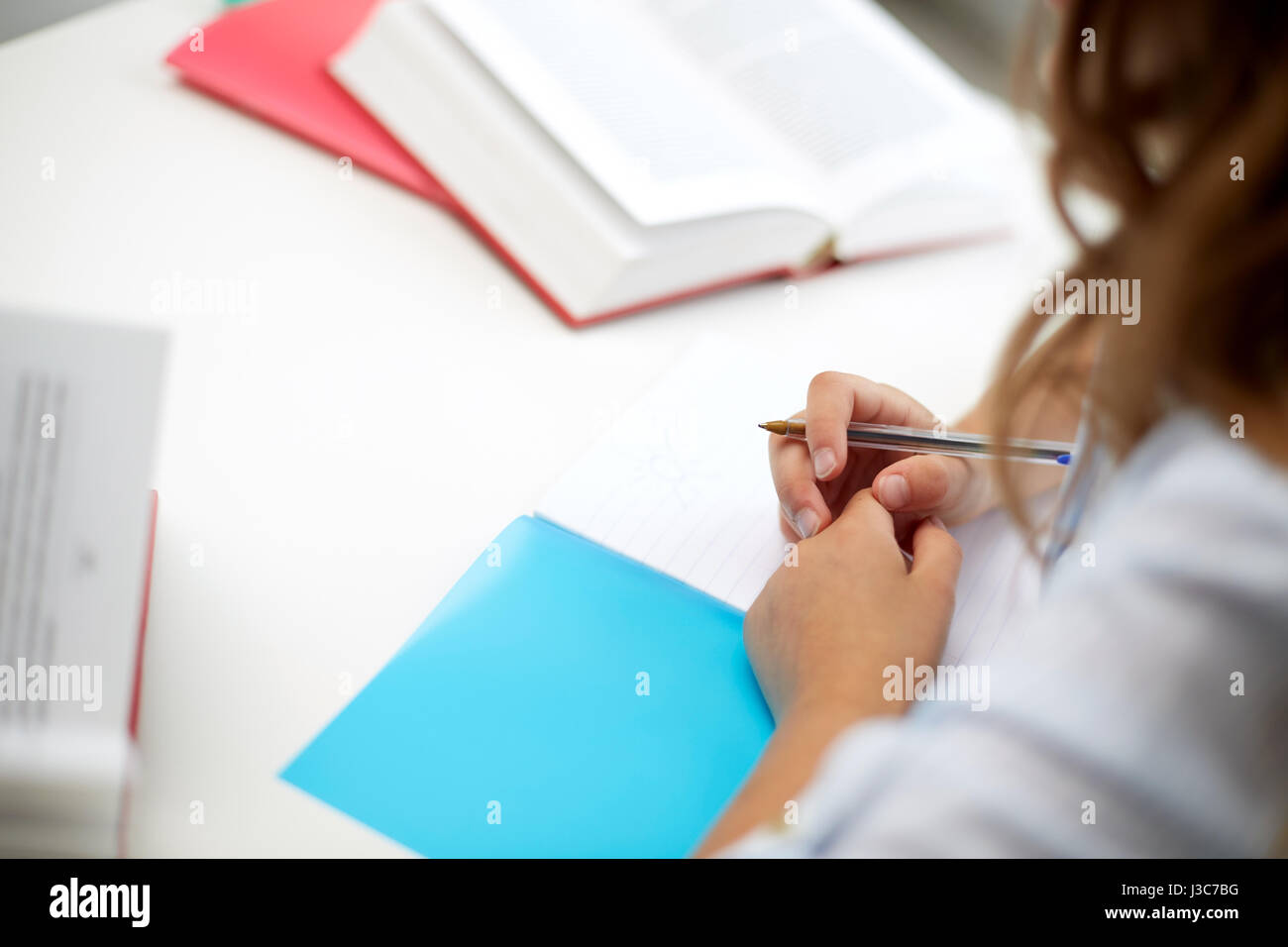 girl with book writing to notebook at school Stock Photo - Alamy