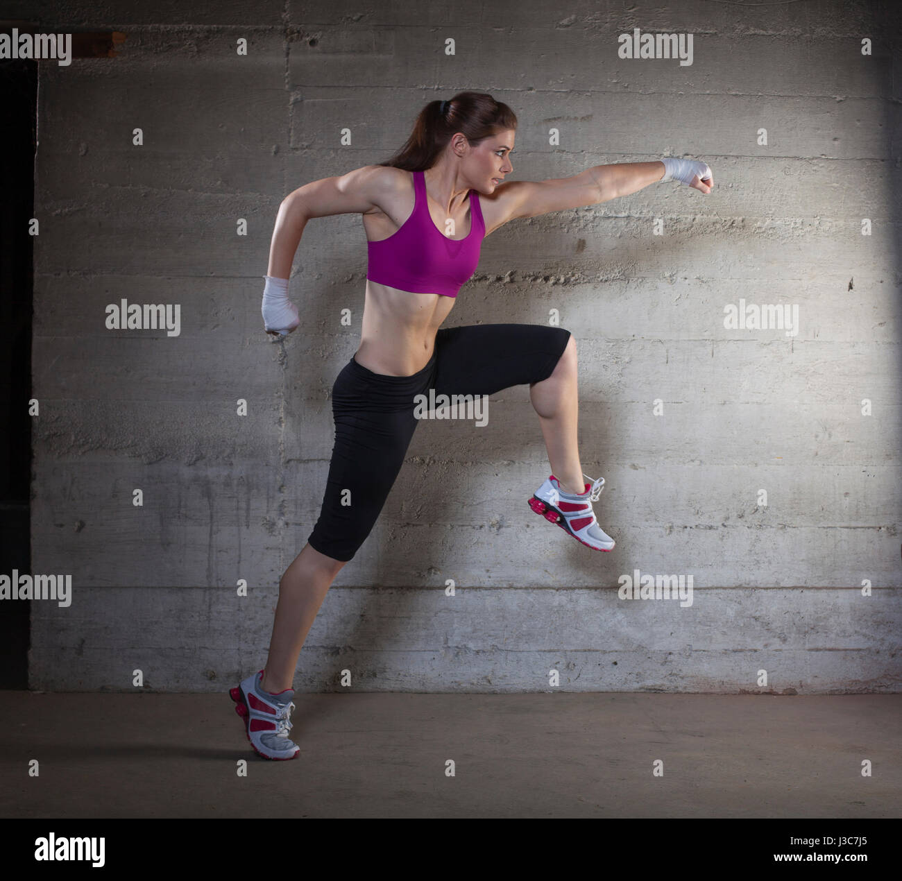 Strong fit athletic woman kicking and throwing punches. Image taken ...