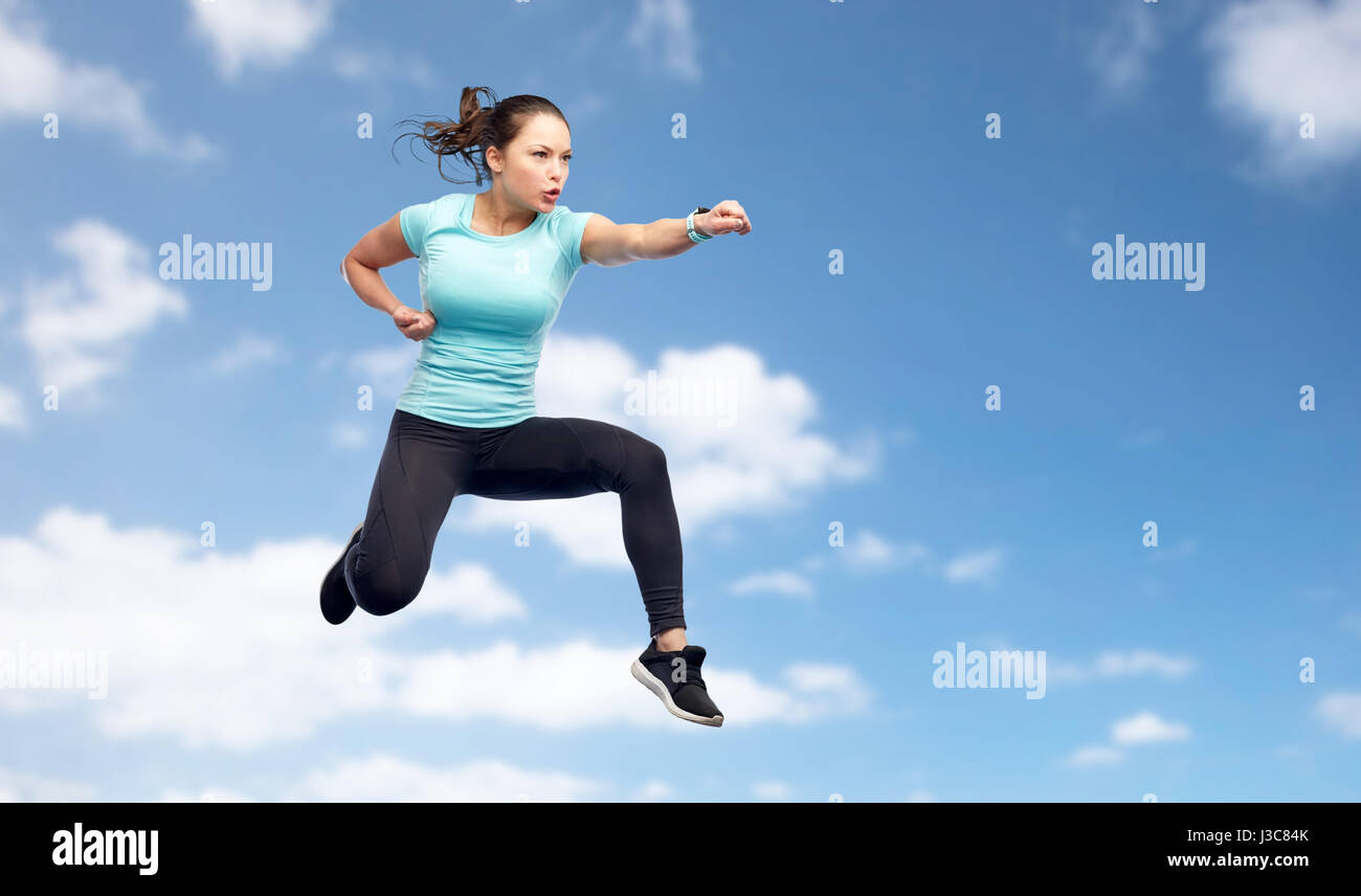 sporty woman jumping in fighting pose over sky Stock Photo - Alamy