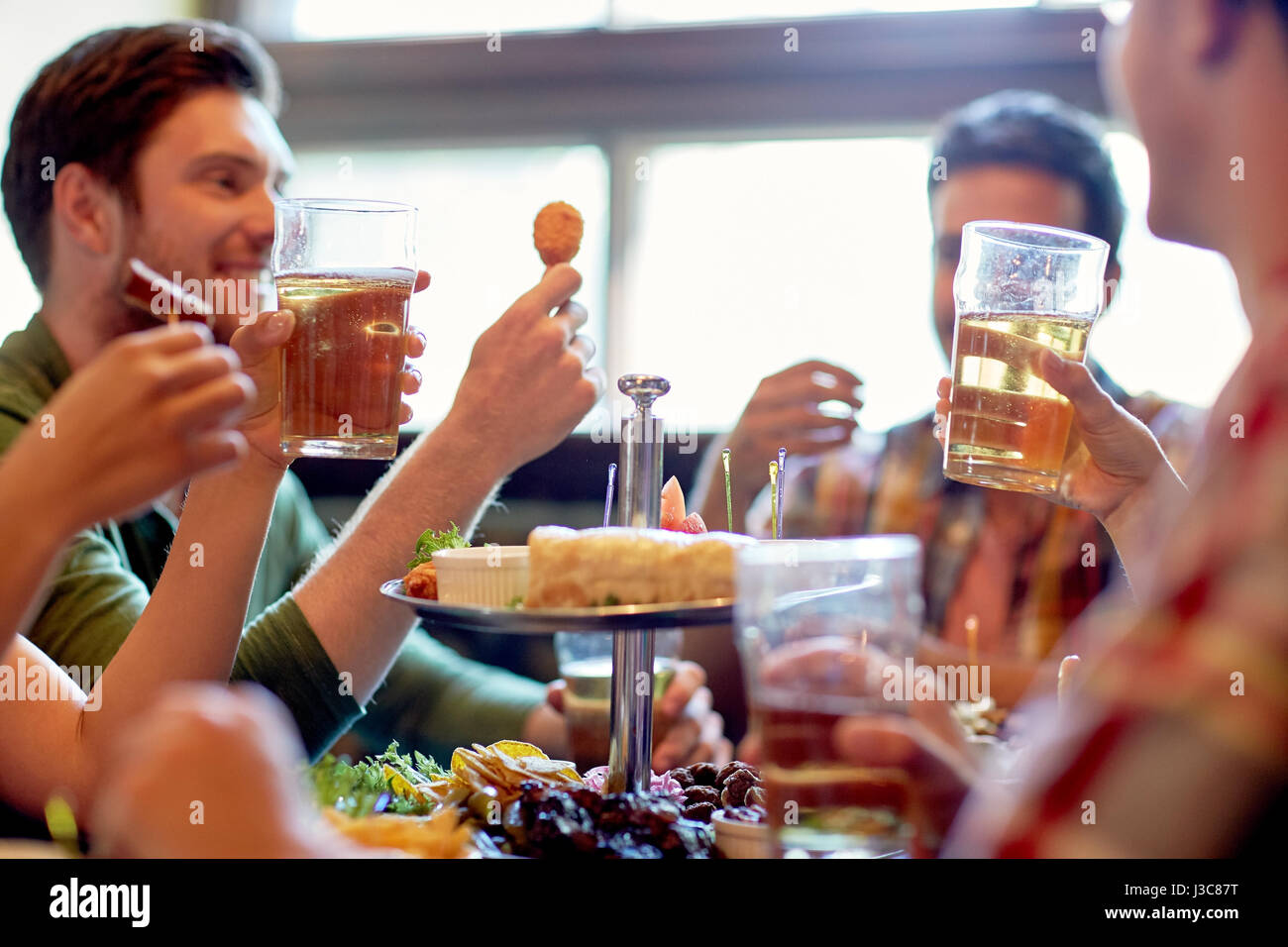 happy friends eating and drinking at bar or pub Stock Photo - Alamy