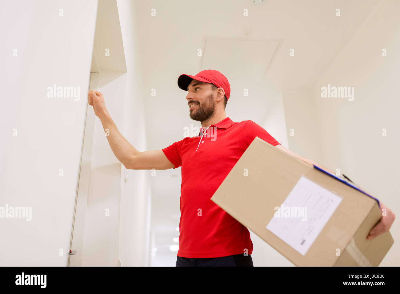 delivery man with parcel box knocking on door Stock Photo - Alamy