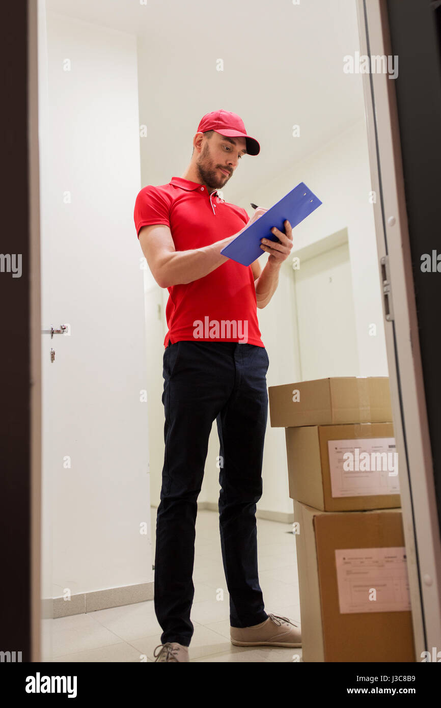 delivery man with boxes and clipboard at door Stock Photo - Alamy