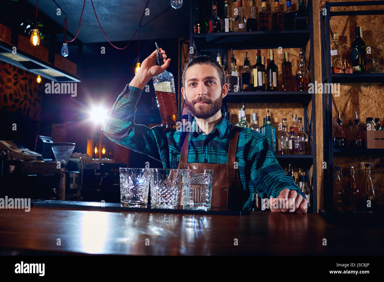 Barman bartender with a bottle of alcohol behind the counter in bar ...