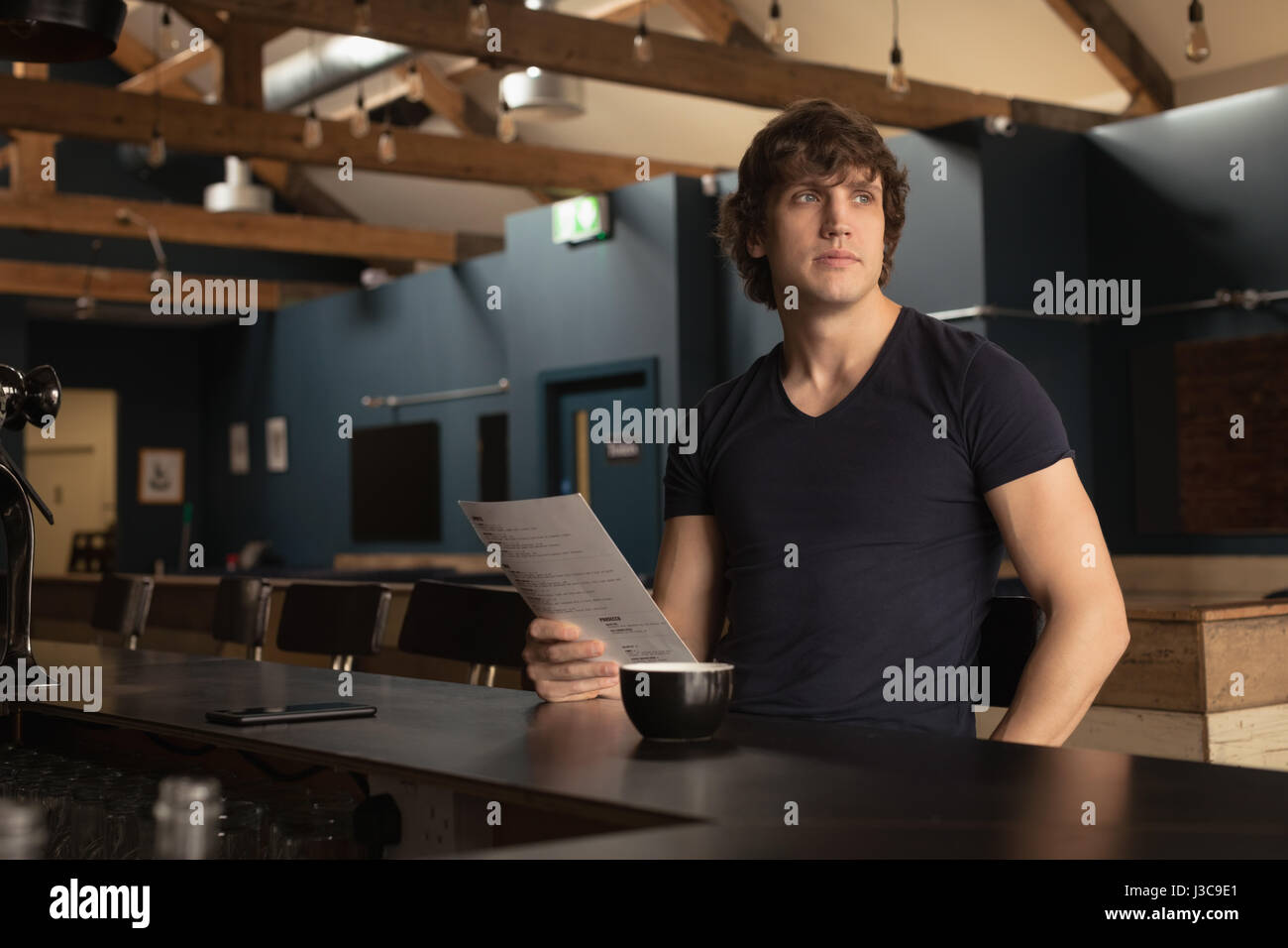 Thoughtful man holding menu card while having coffee in restaurant ...