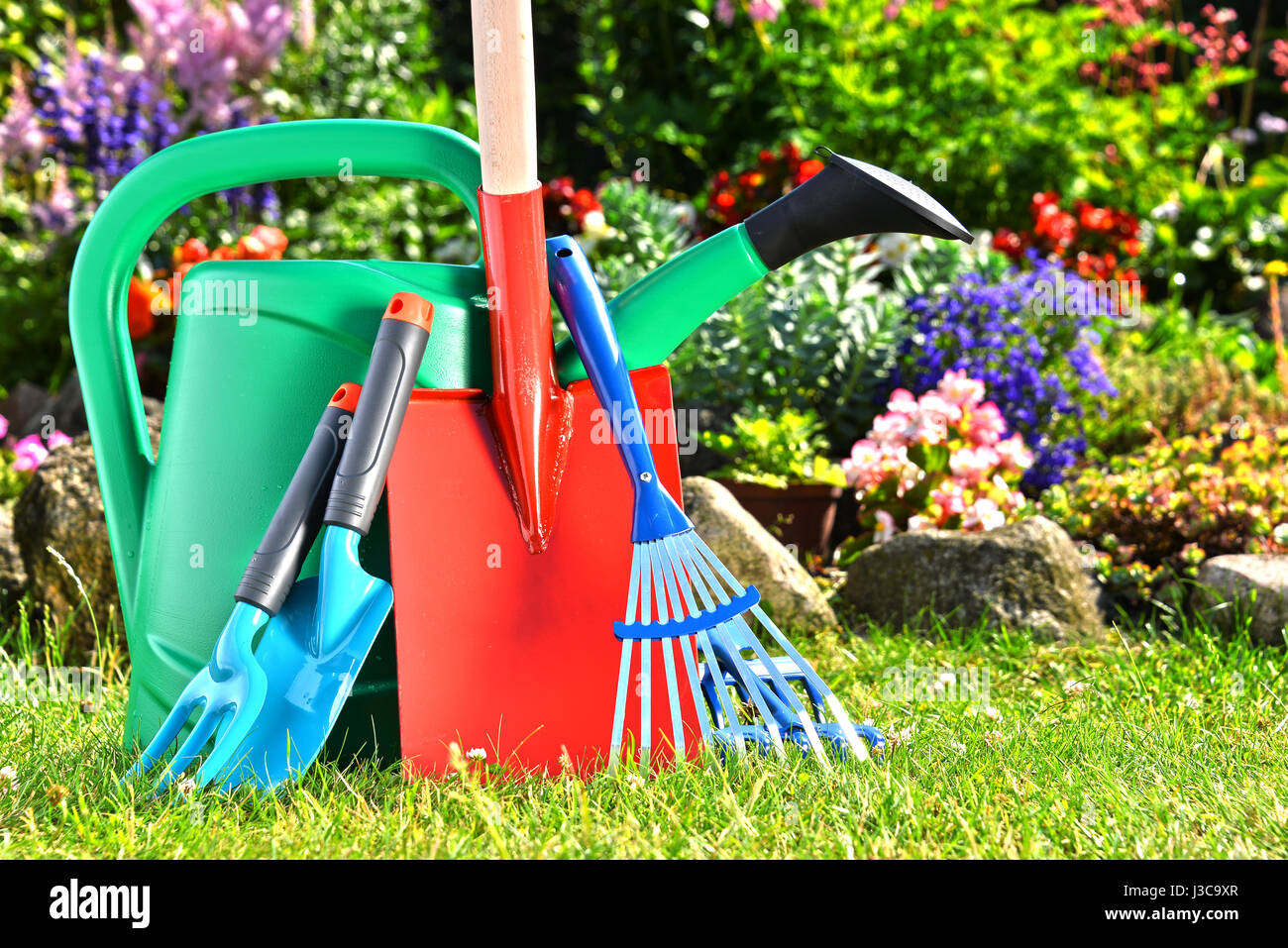 Watering can and tools in the garden Stock Photo - Alamy