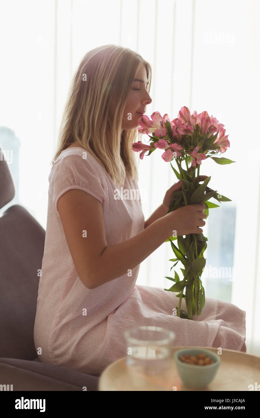 Beautiful woman smelling flower at home Stock Photo - Alamy